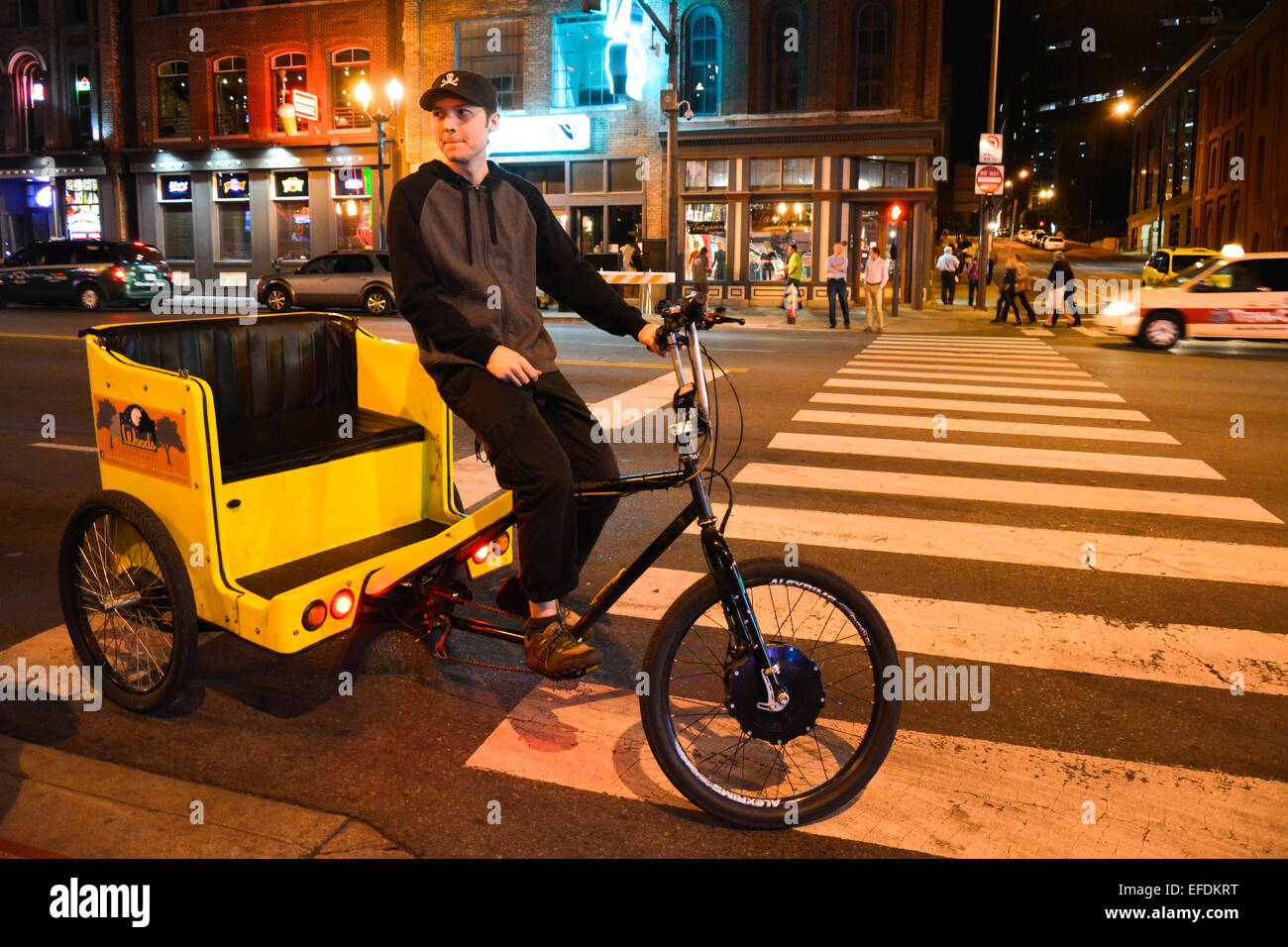 A pedicab driver pauses in a crosswalk as he looks for fares at night ...