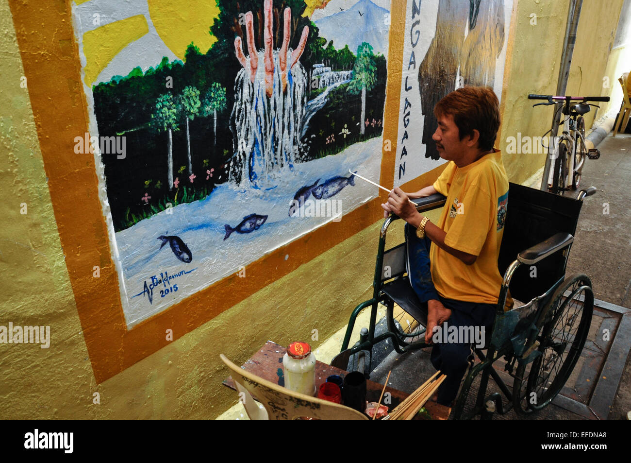 A PWD artist paints a mural as he participates during the Obra sa Pader ...