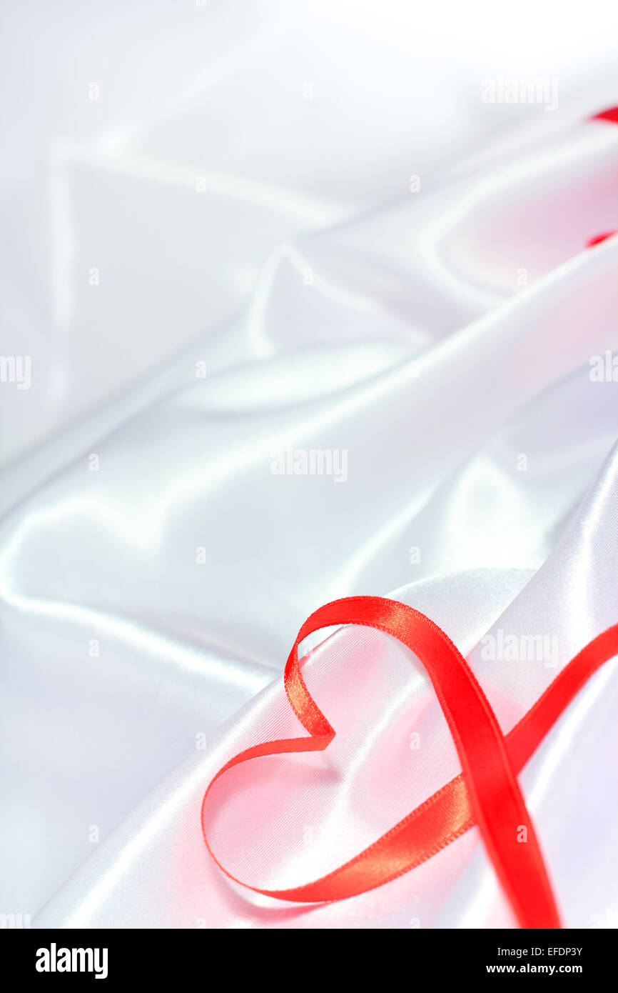 Red satin glossy ribbon heart over white silk background Stock Photo ...