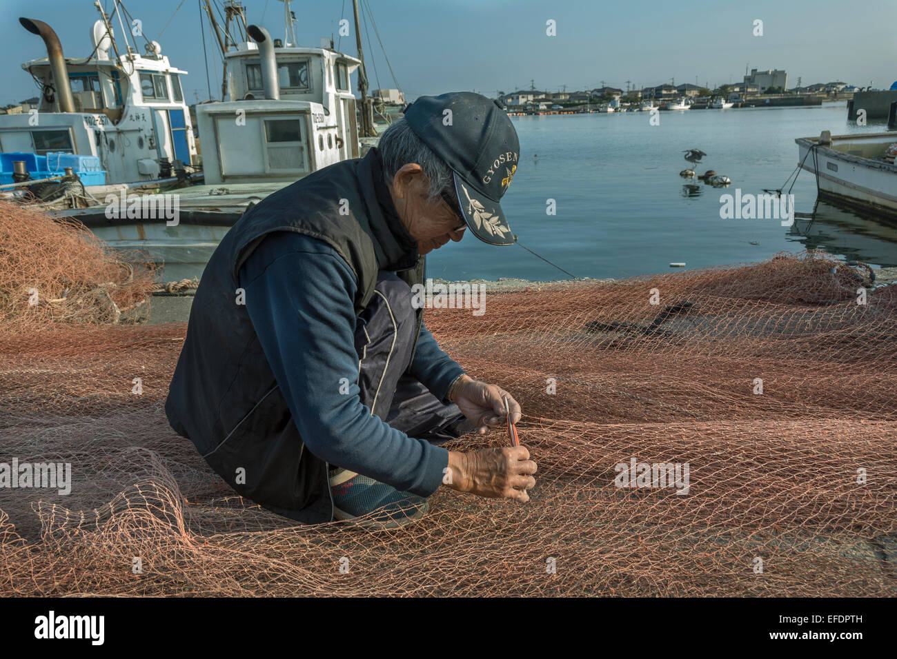 Old man repairing fishing nets by hand, Naruto Harbor, Shikoku Island ...