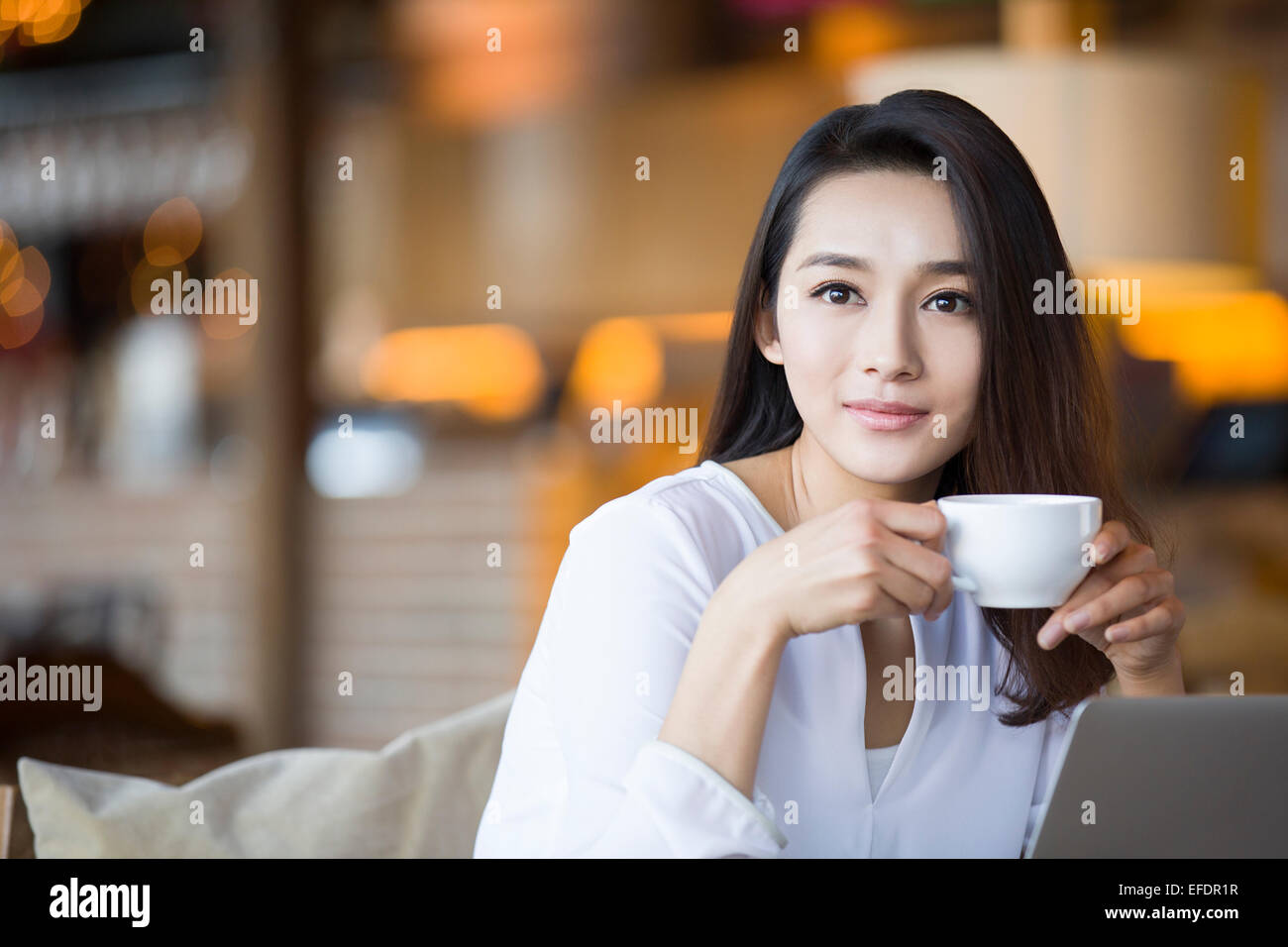 Young woman drinking coffee in cafe Stock Photo - Alamy