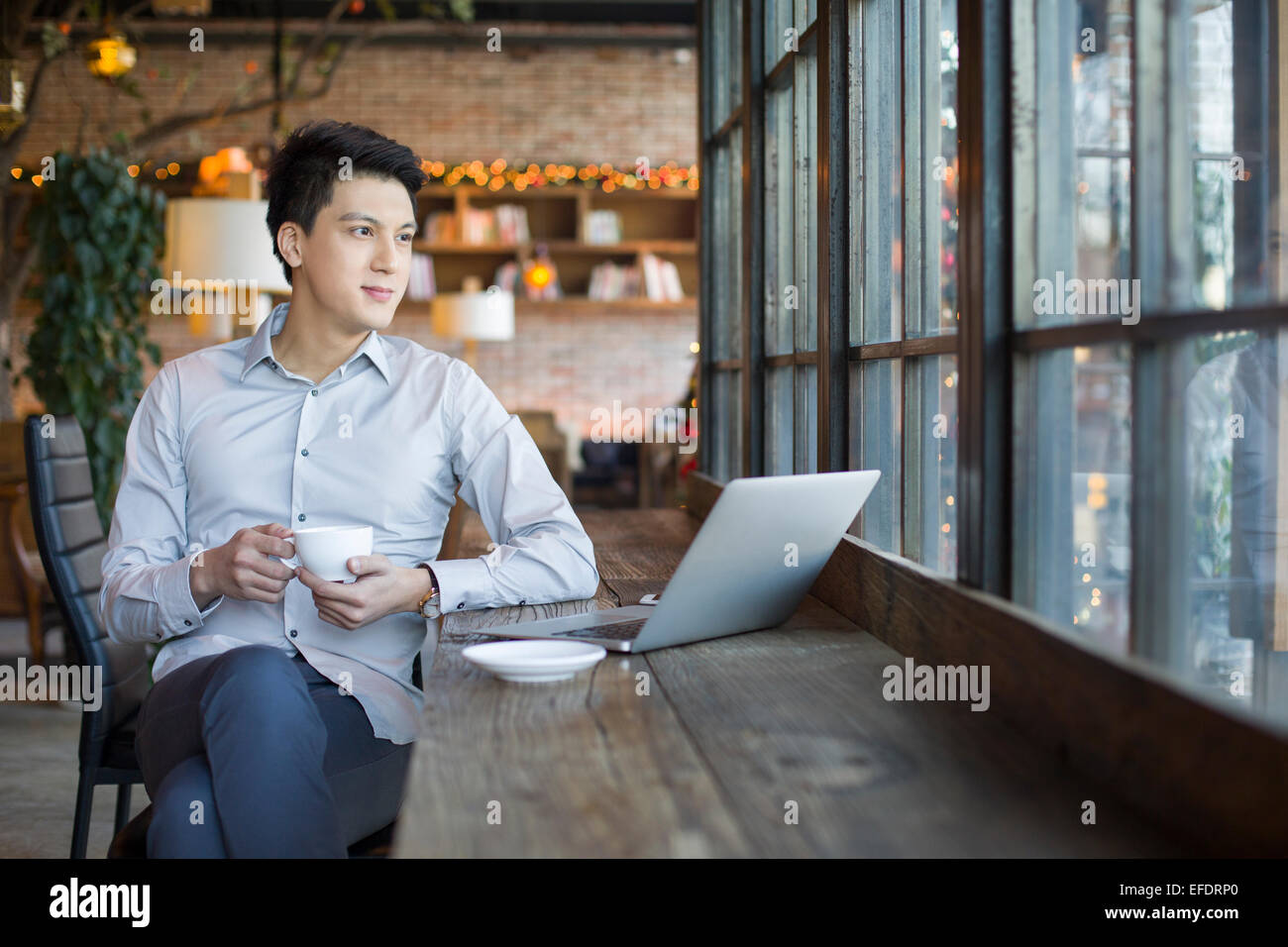 Young man drinking coffee in cafe Stock Photo - Alamy