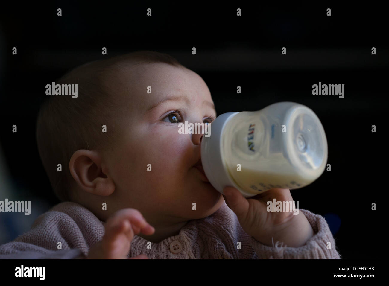 A ten month old baby girl peering out of the window while feeding ...
