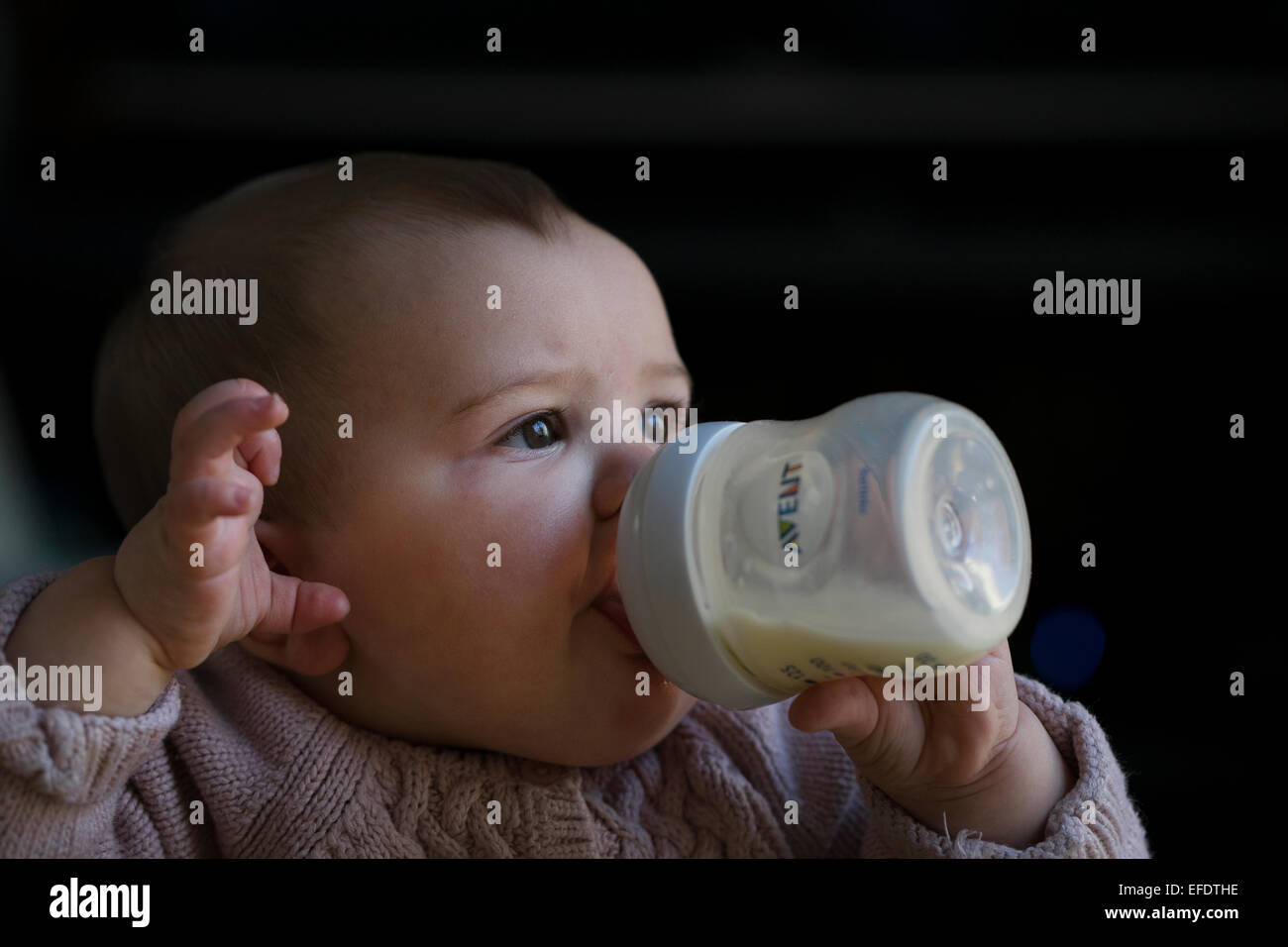 A ten month old baby girl peering out of the window while feeding ...