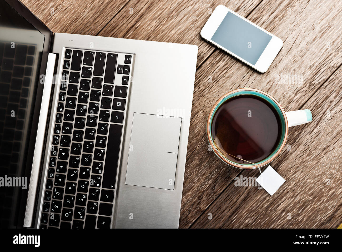 Office workplace with open laptop and cup of tea on wooden desk Stock ...
