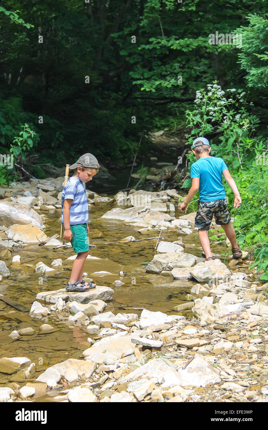 Two kids playing near a mountain stream Stock Photo - Alamy