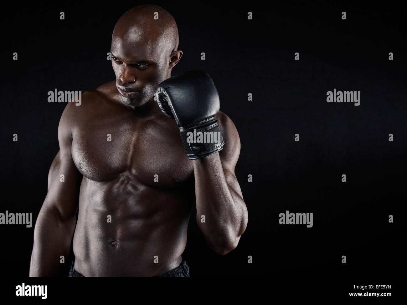 Portrait of determined young boxer thinking of his moves on black ...