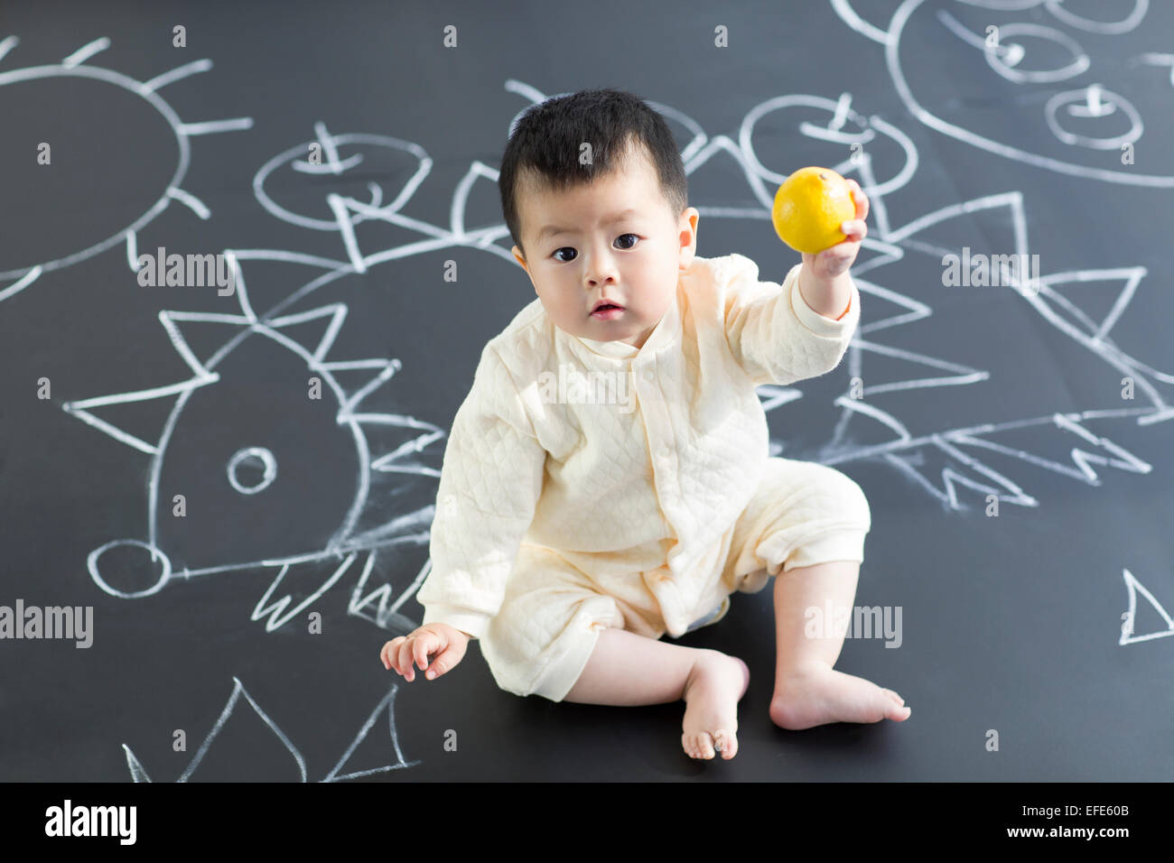 Cute baby sitting on drawing board Stock Photo - Alamy