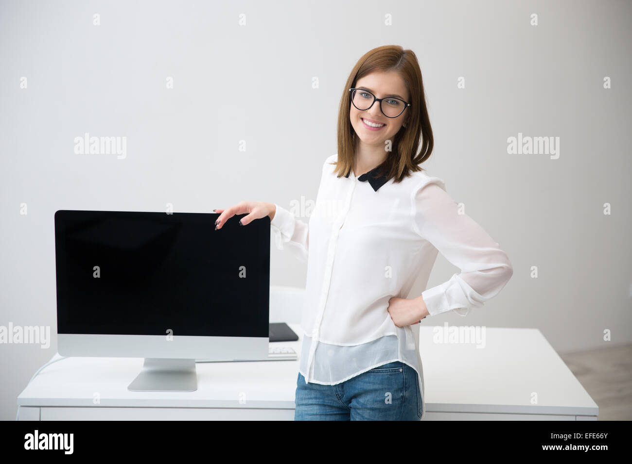 Smiling business woman presenting blank monitor screen Stock Photo - Alamy