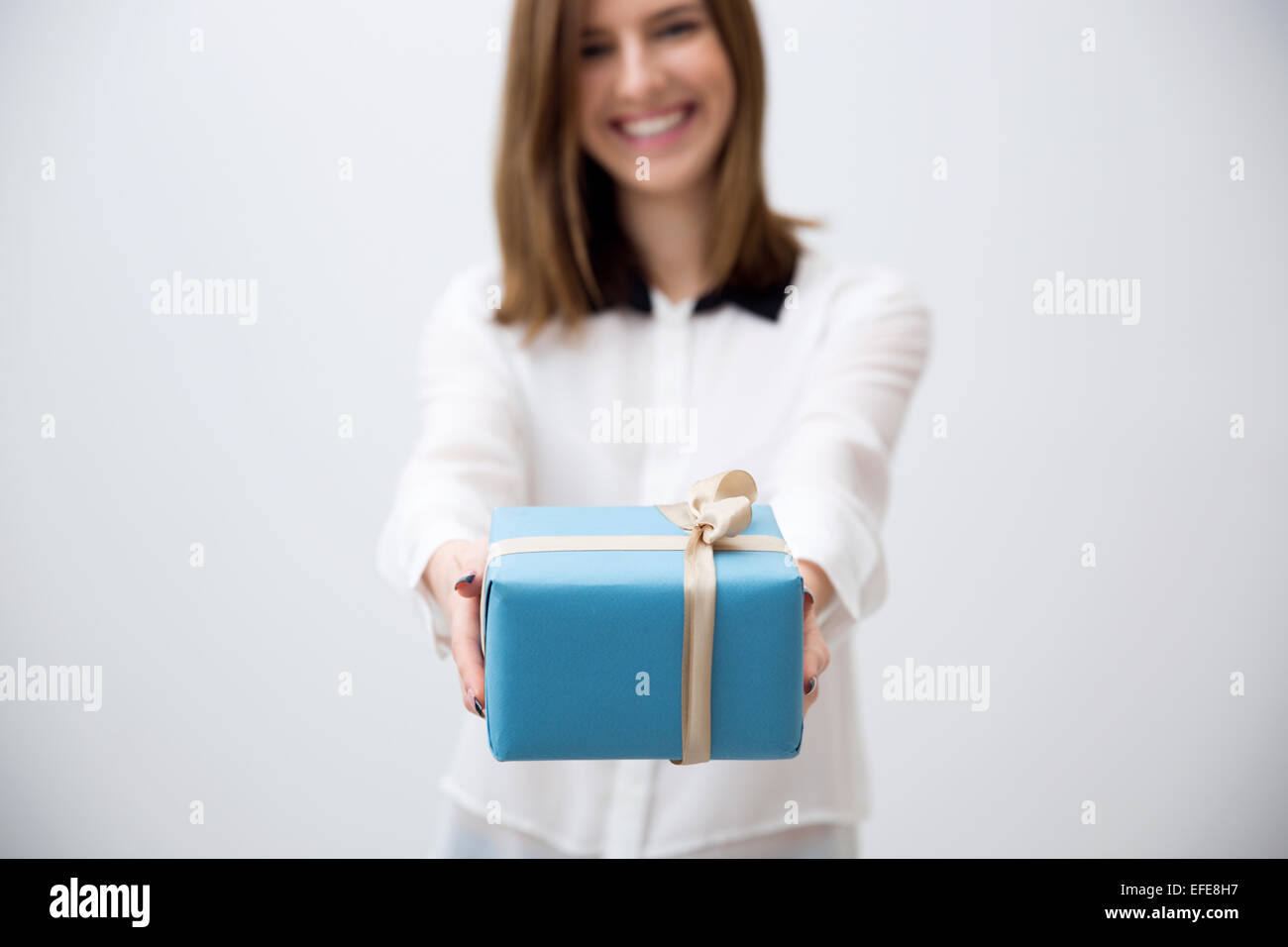 Smiling young woman giving gift. Focus on a gift Stock Photo - Alamy