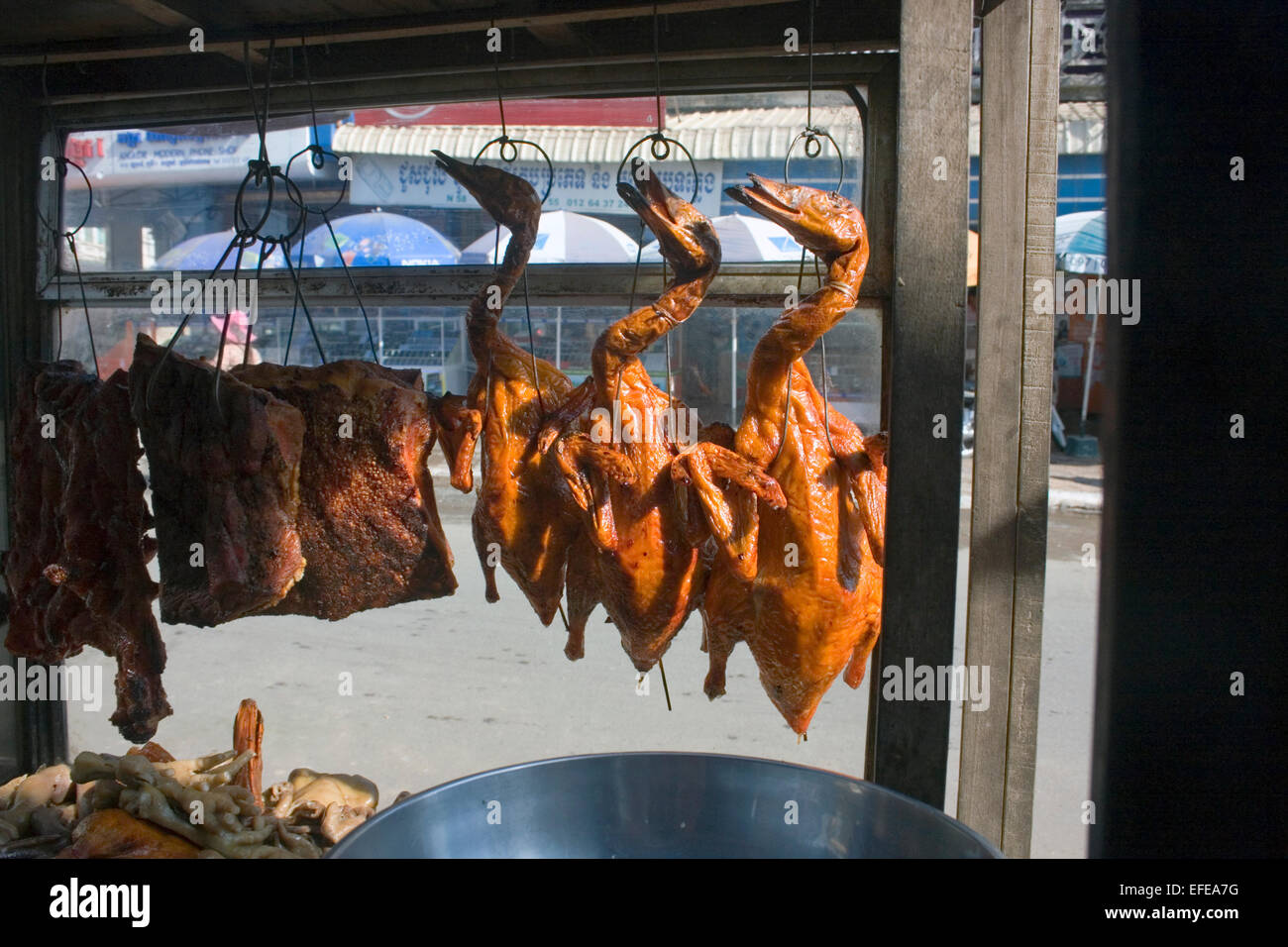 Roasted ducks are hanging on a mobile food cart on a city street in ...