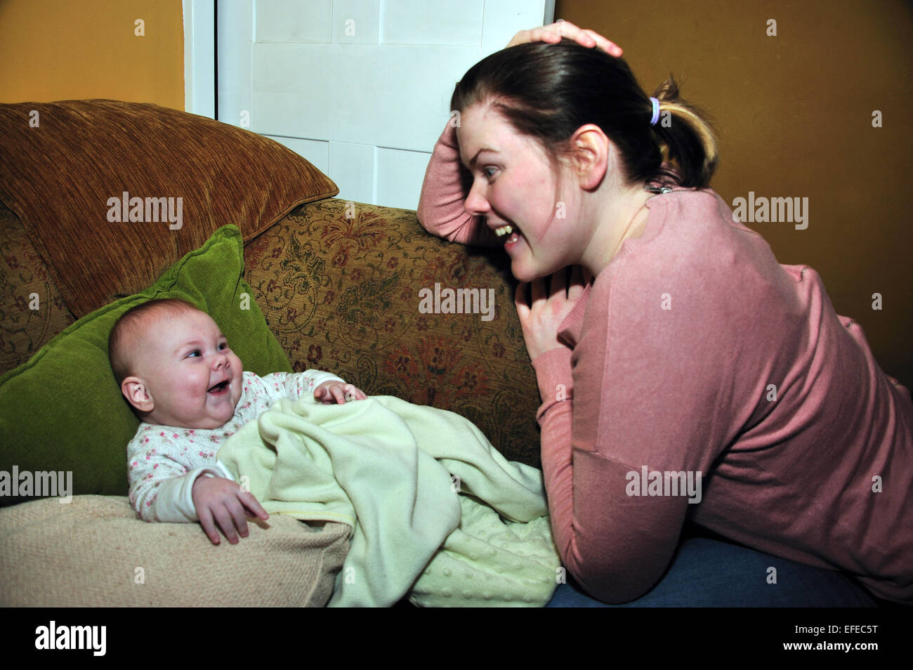 A mother and her four month old baby smiling and interacting together ...