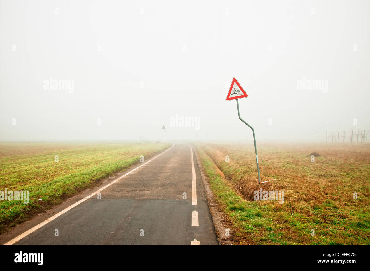 Foggy empty rural road with danger sign Stock Photo - Alamy