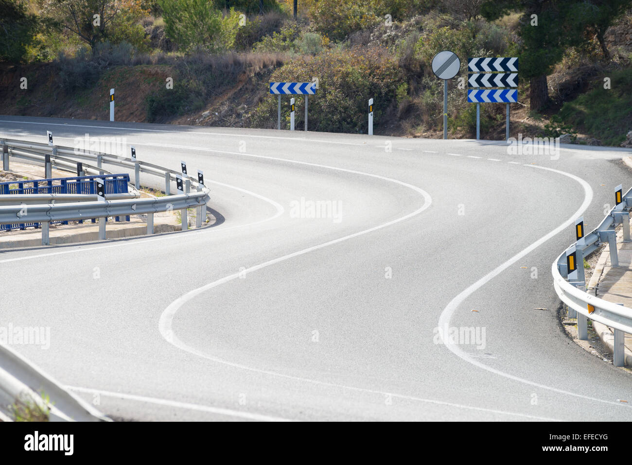 A tight bend in a road with crash barriers Stock Photo - Alamy
