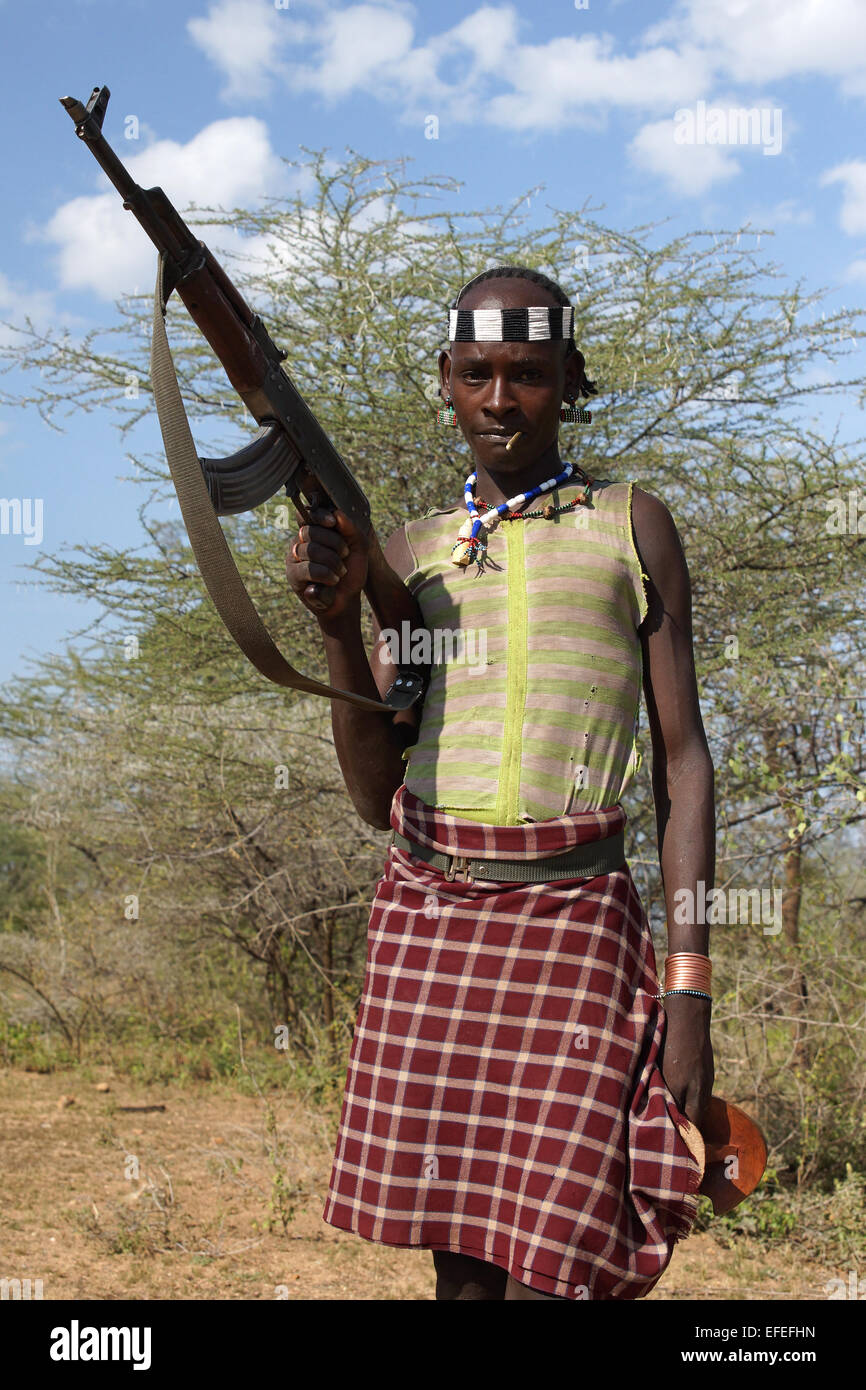 TURMI, ETHIOPIA - NOVEMBER 19, 2014: Young Hamer man with automatic gun ...