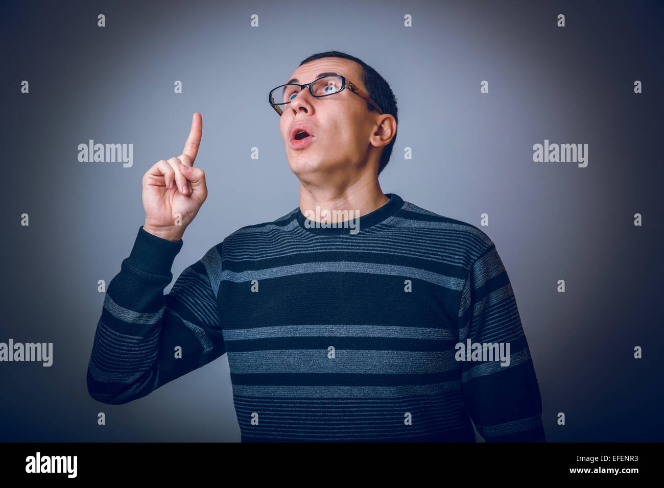 male of European appearance brunet showing thumb up on a gray ba Stock ...