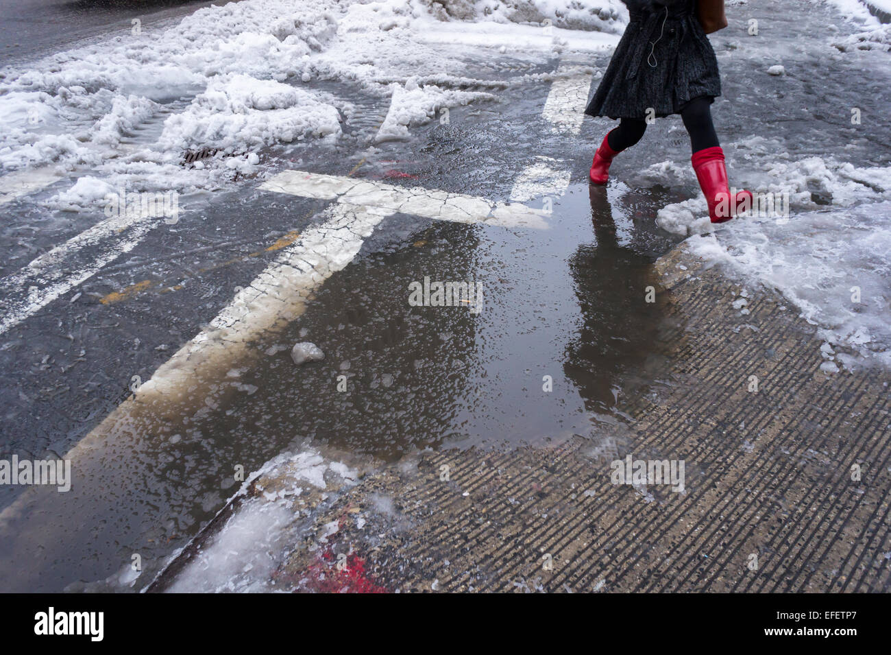Pedestrians slog through puddles of slush and snow at street crossings ...