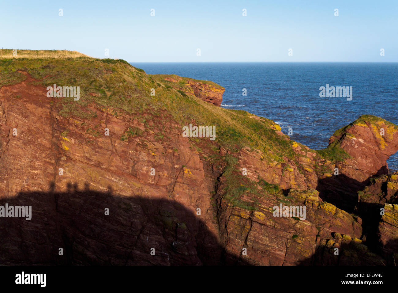 Silhouette of walkers looking across a steep sandstone cliff face at ...