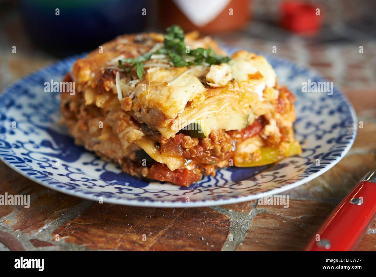 Lasagna on a plate from a side view with natural light with veggies and ...