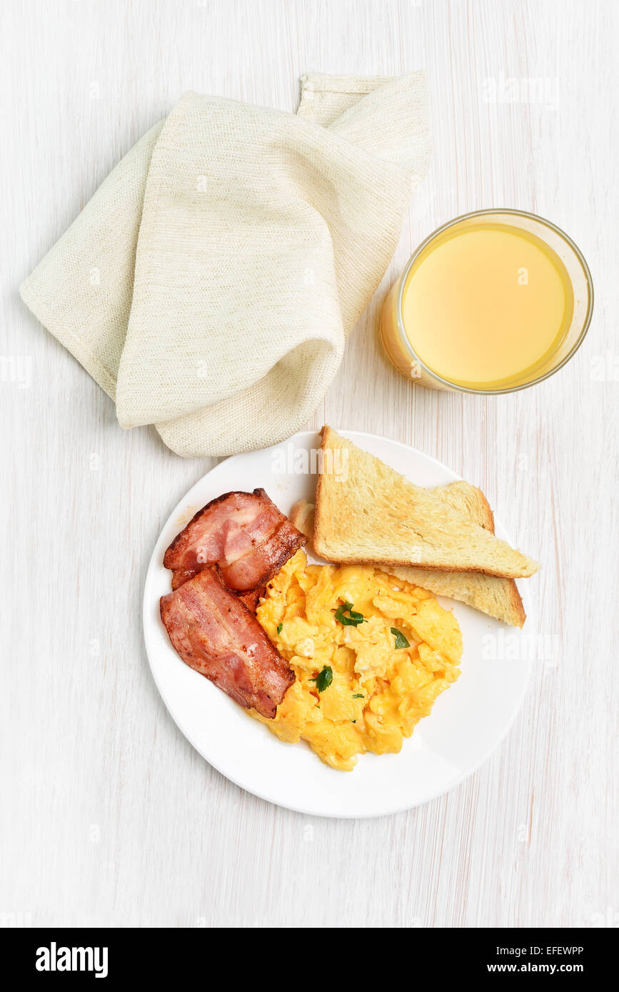 Scrambled eggs, bacon, toasts and orange juice on white wooden table, top view Stock Photo - Alamy
