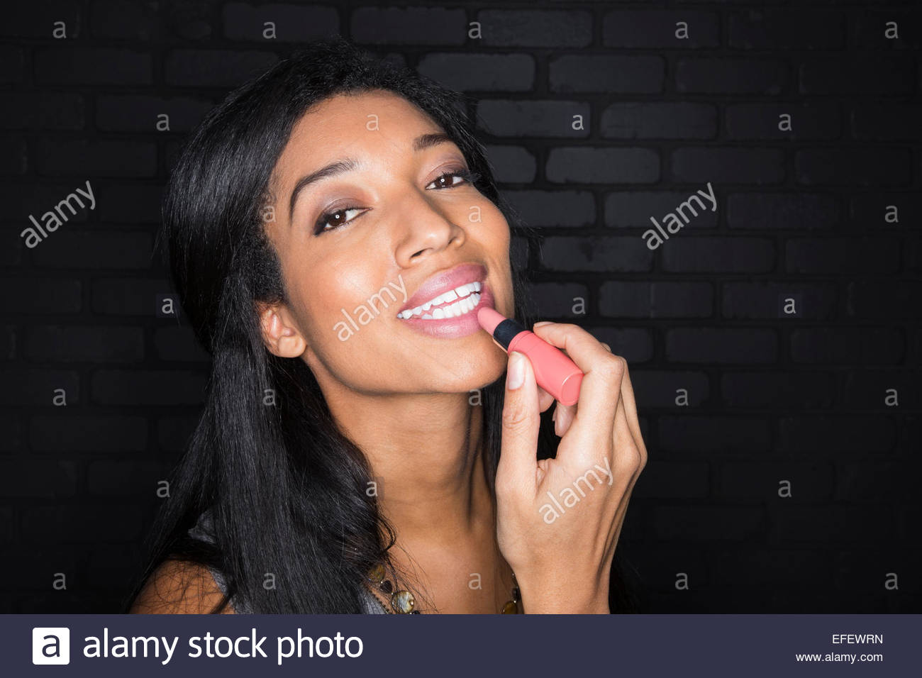 Portrait of woman applying pink lipstick Stock Photo - Alamy