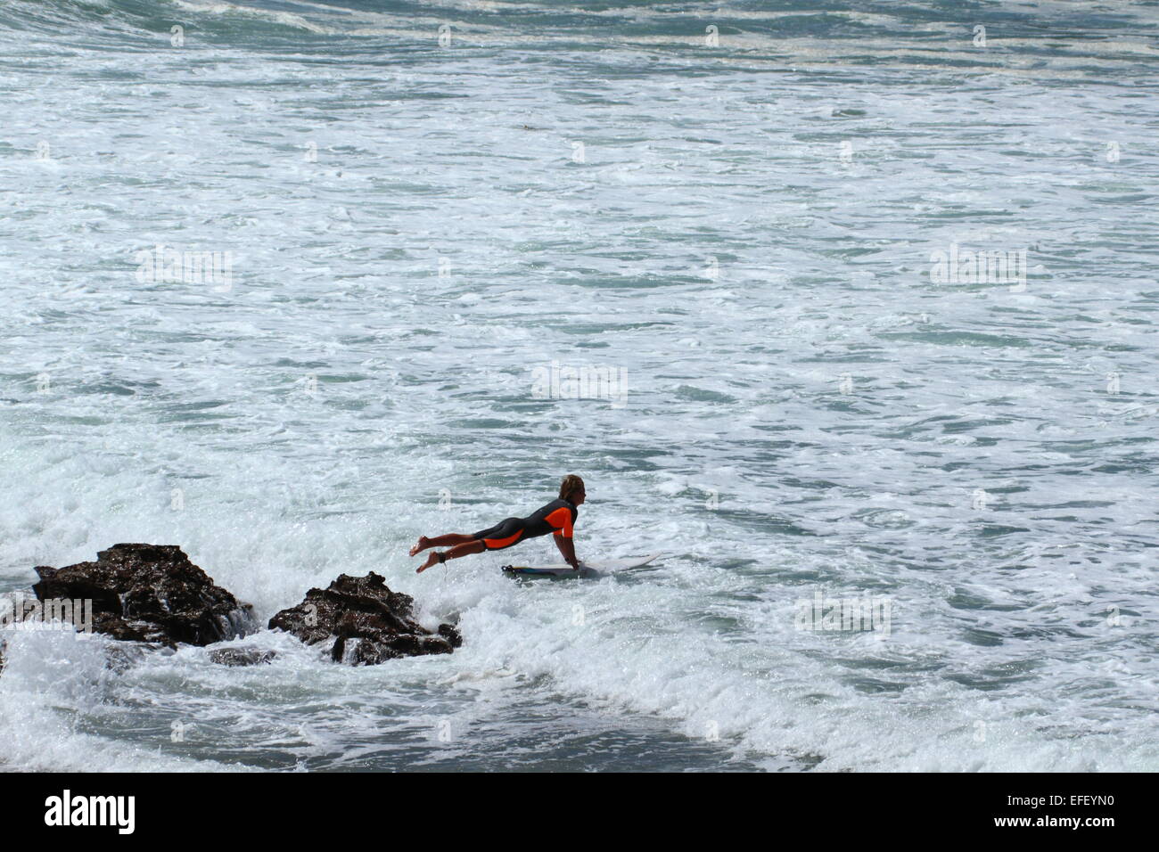 A young surfer leaps from rocks into the surf at Sandon Point, Bulli ...