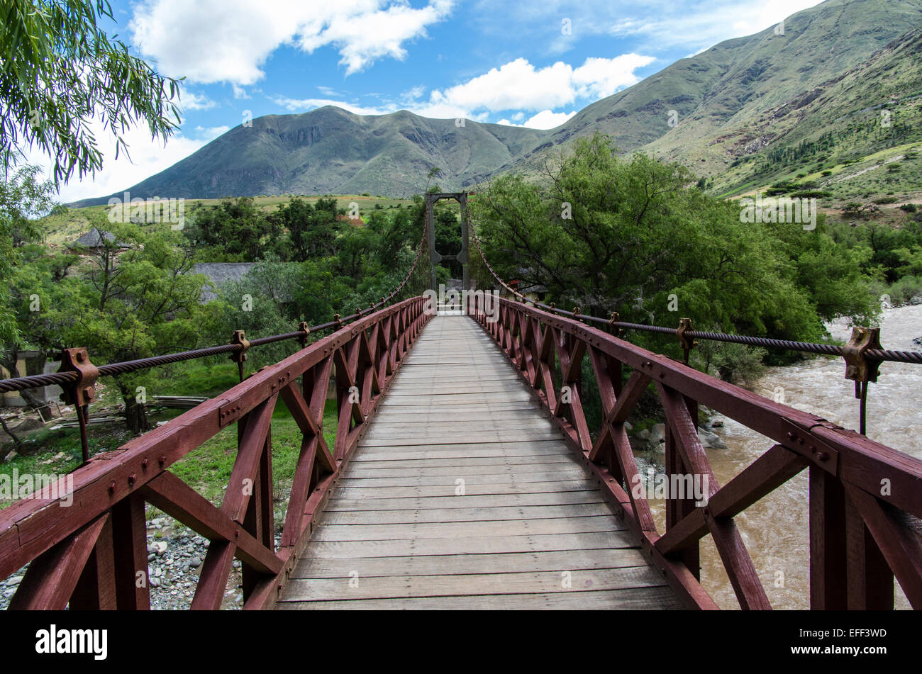 Pedestrian bridge in the upper Huallaga river. Andes mountains range ...