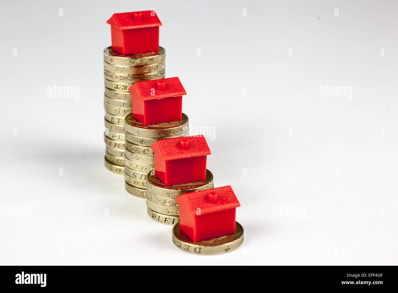 Red monopoly houses on top of piles of pound coins Stock Photo - Alamy