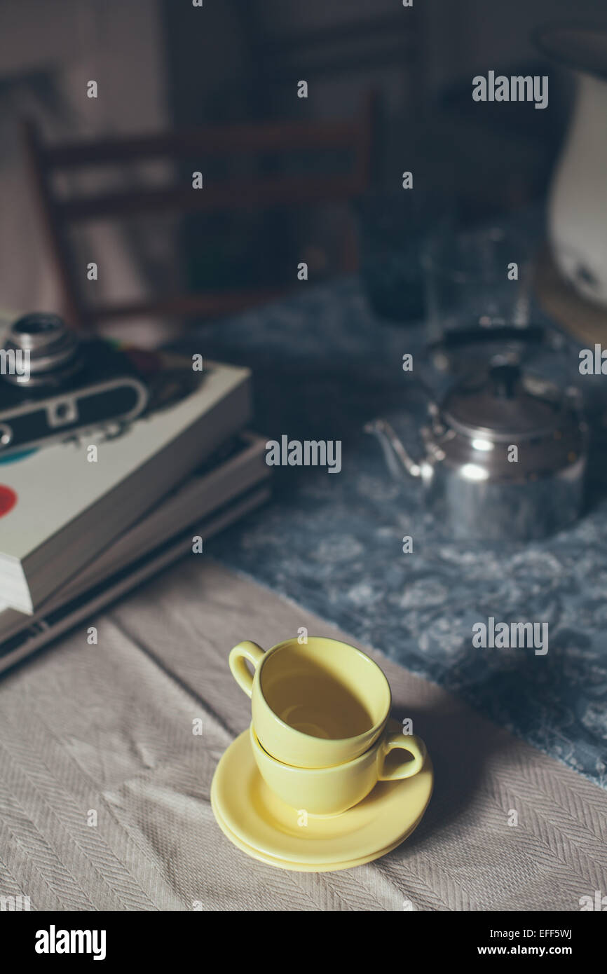 Still life scene with 2 yellow tea cups a teapot, a vintage camera and ...