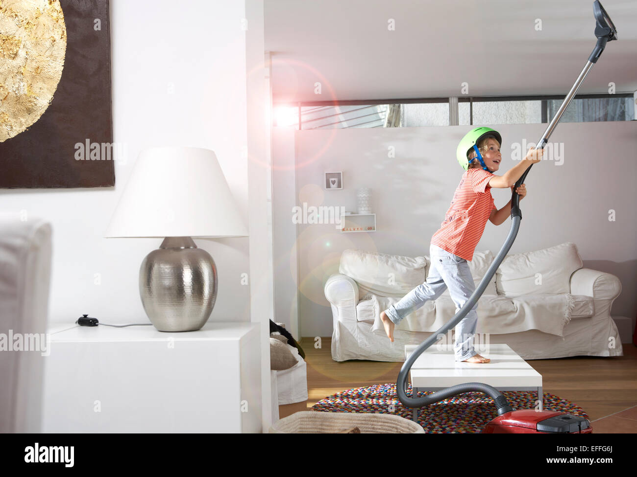 Boy in living room hoovering the ceiling Stock Photo - Alamy