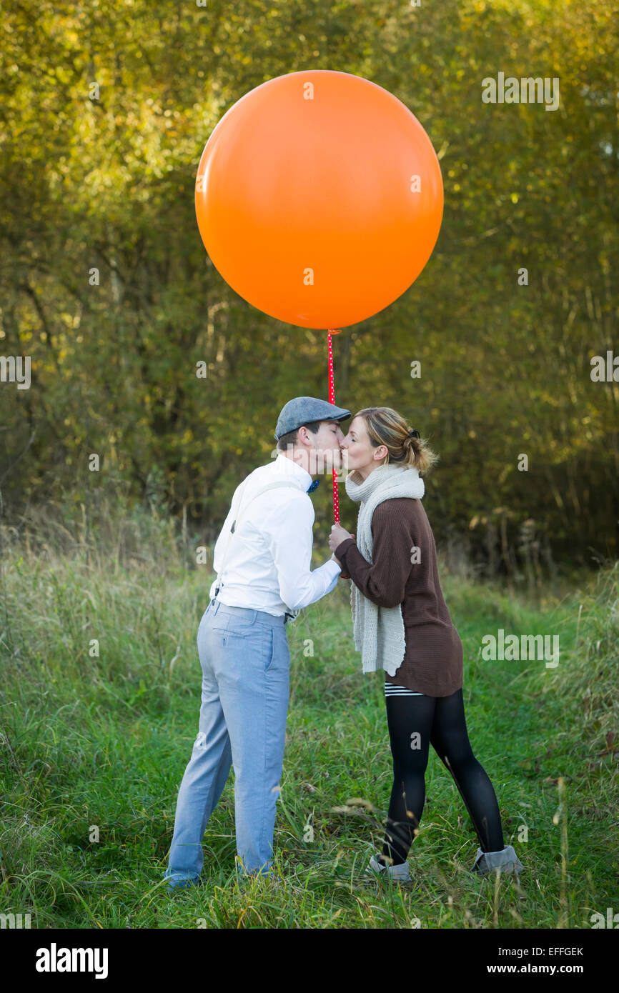Couple with balloon on meadow kissing Stock Photo - Alamy