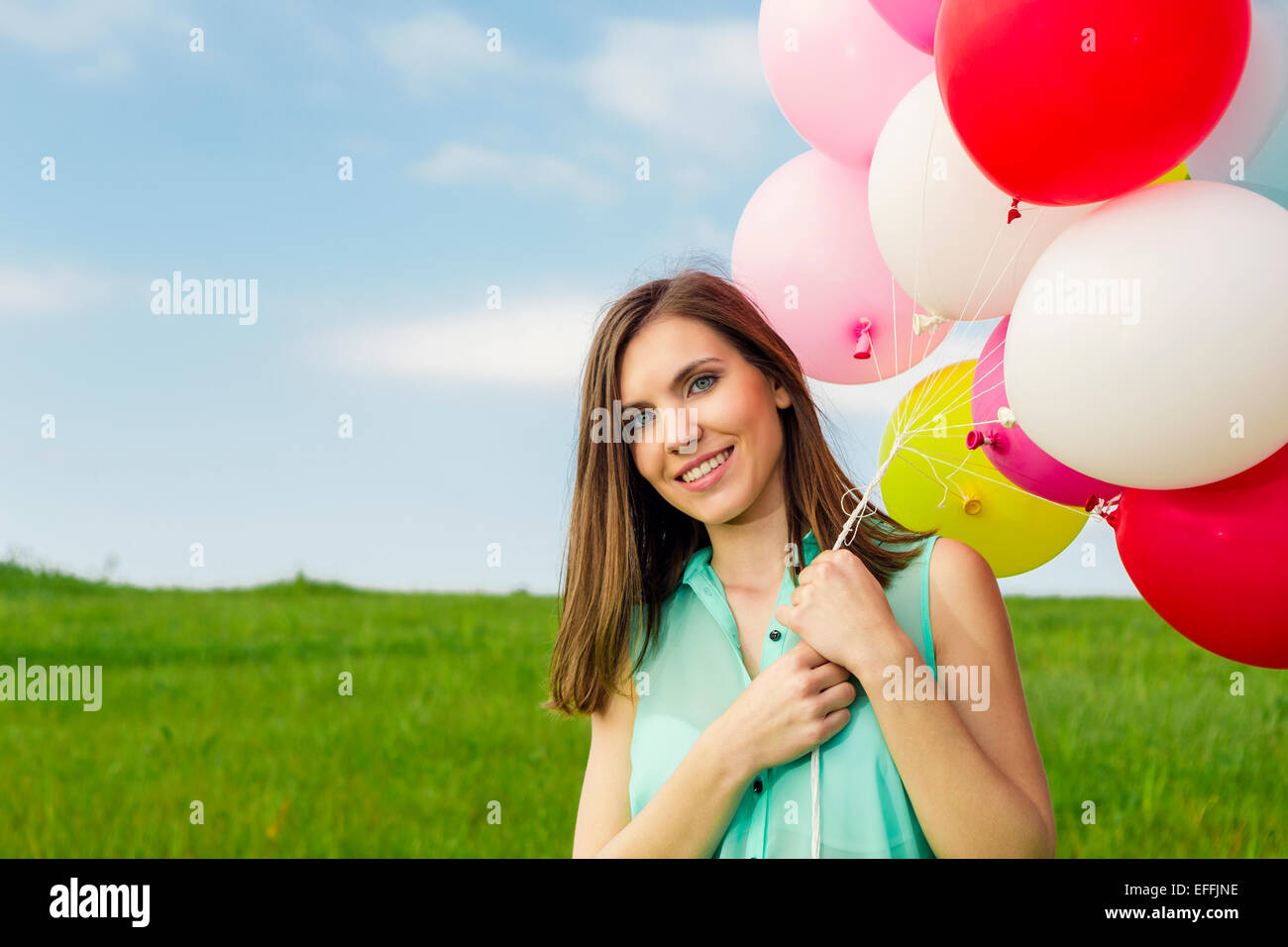 Young beautiful woman with colorful balloons on a green meadow Stock ...