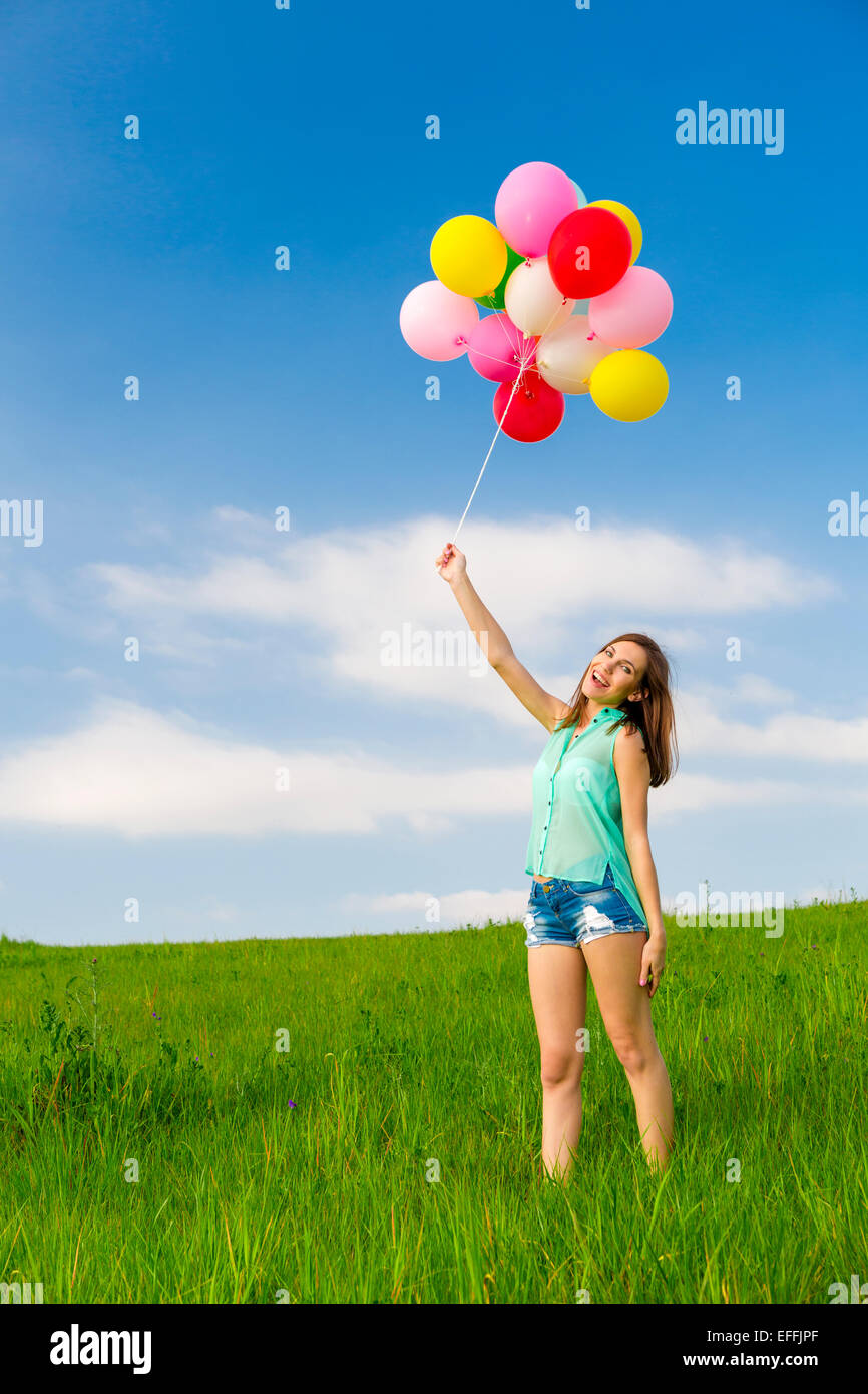 Young beautiful woman with colorful balloons on a green meadow Stock ...