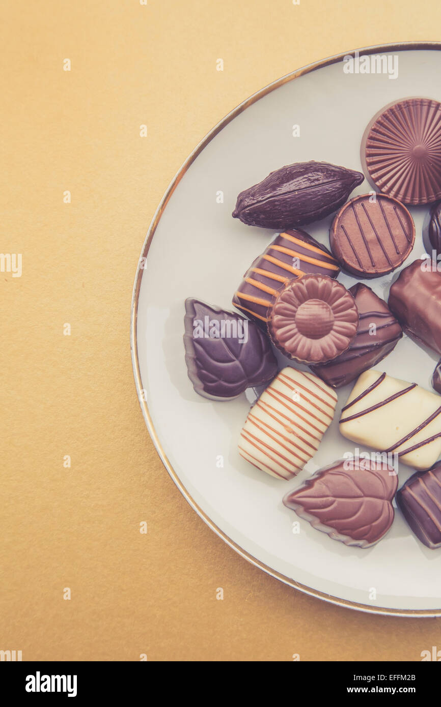 Chocolates on plate and yellow background Stock Photo - Alamy