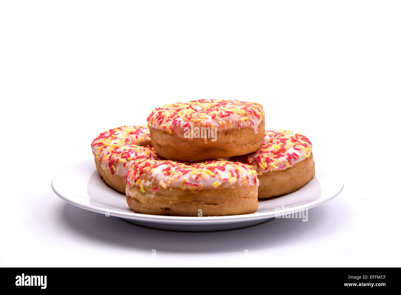 A selection of iced ring donuts on a plate against a white background ...