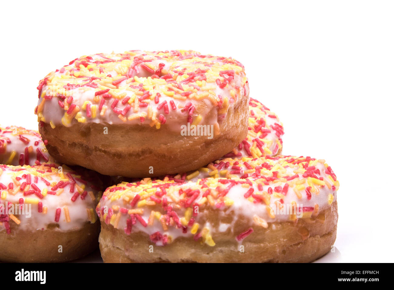 Close up of a selection of iced ring donuts against a white background ...