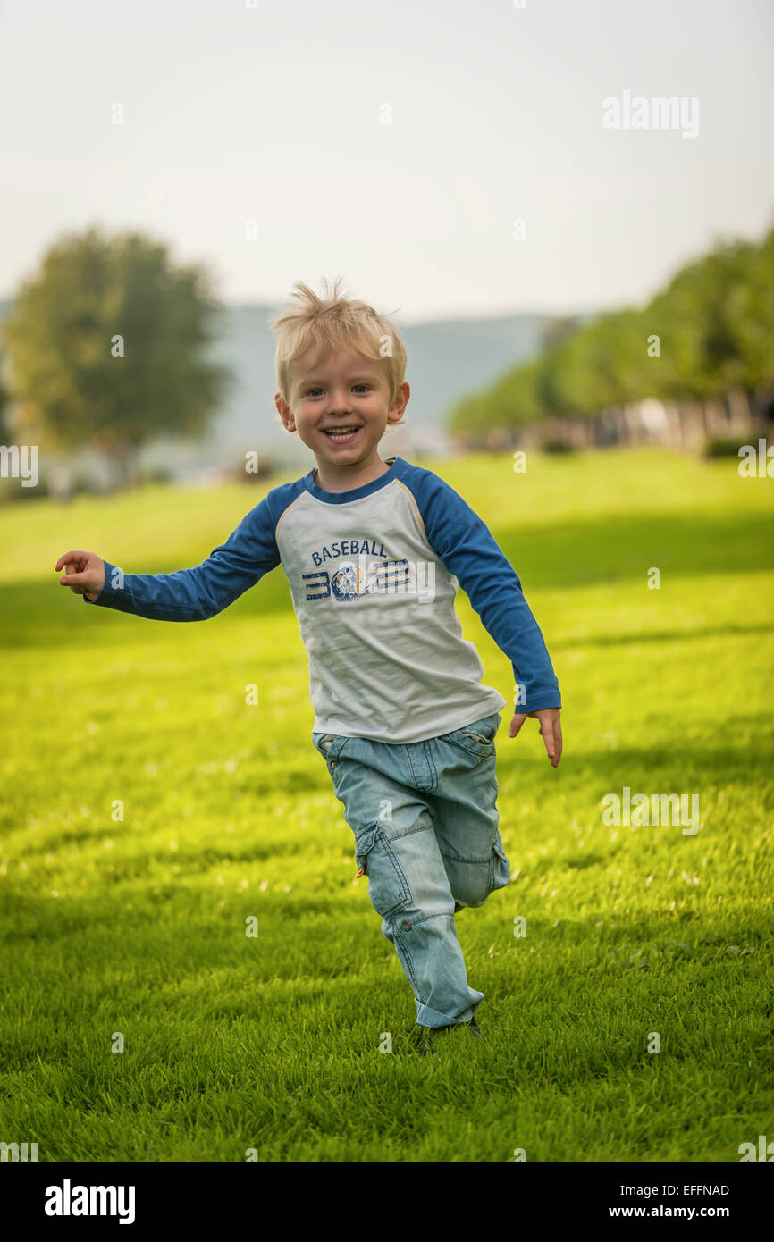 Happy boy running on meadow Stock Photo - Alamy