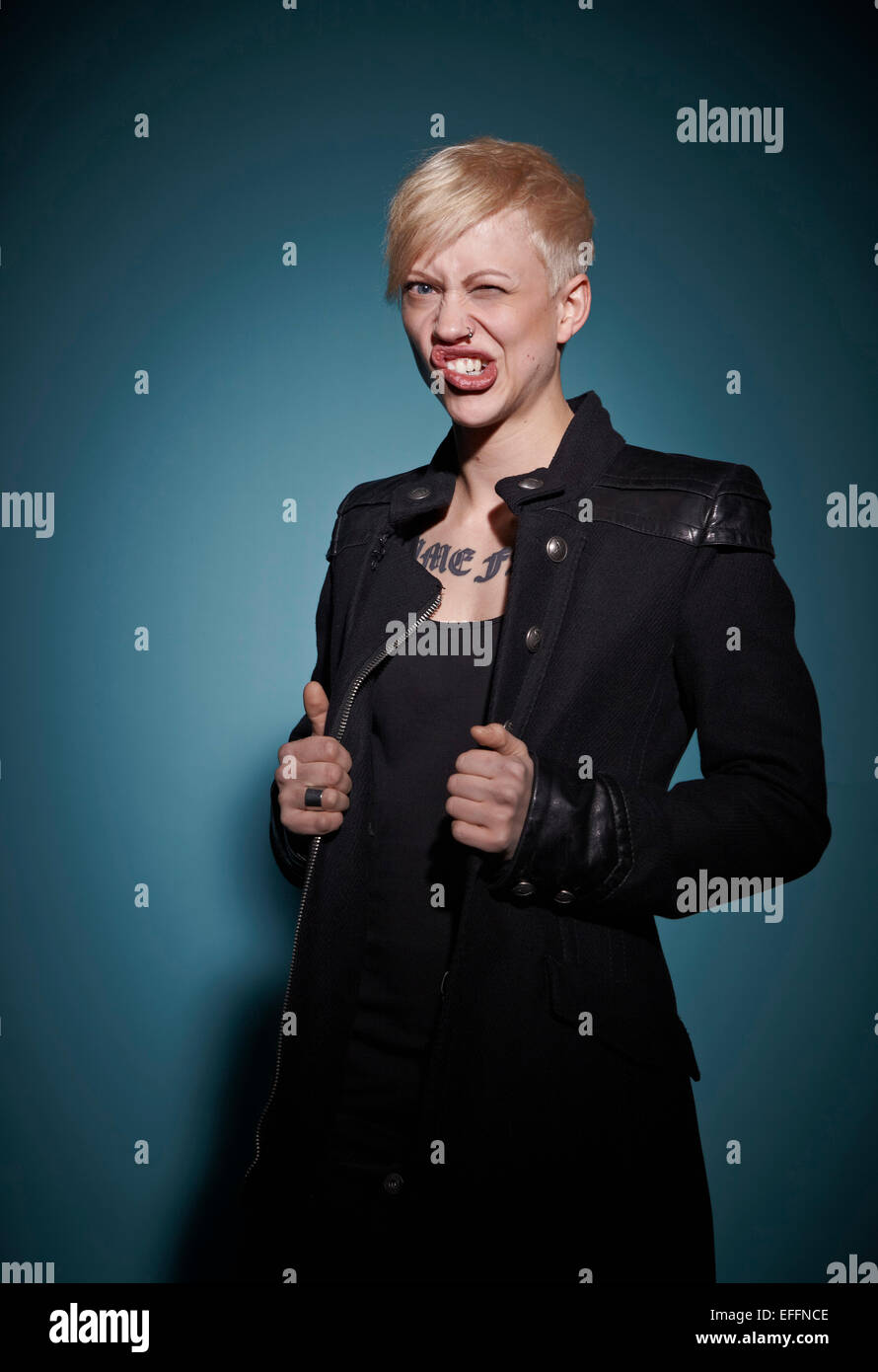 Portrait of aggressive young blond woman dressed in black in front of ...
