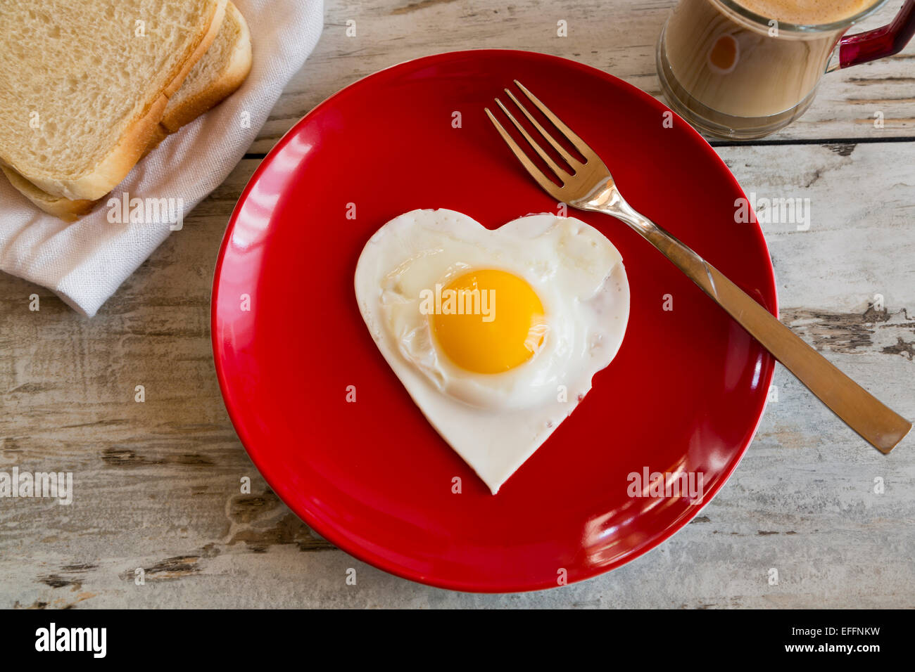 Heart-shaped fried egg on red plate Stock Photo - Alamy