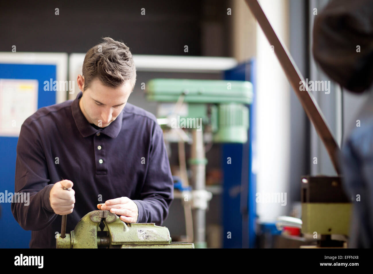 Young technician working at a bench vice in an industrial hall Stock ...