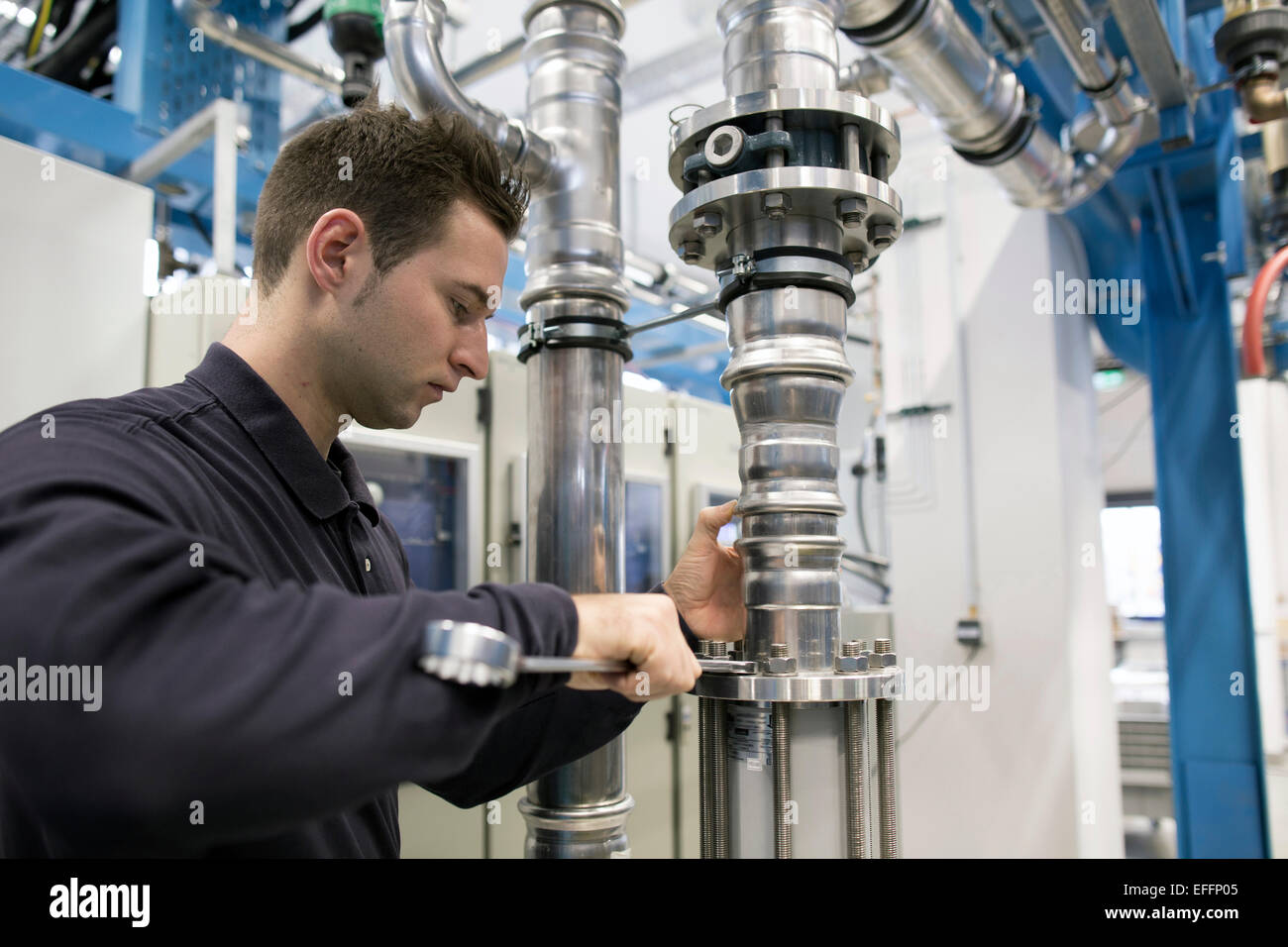Young technician checking a pipe in an industrial hall Stock Photo - Alamy