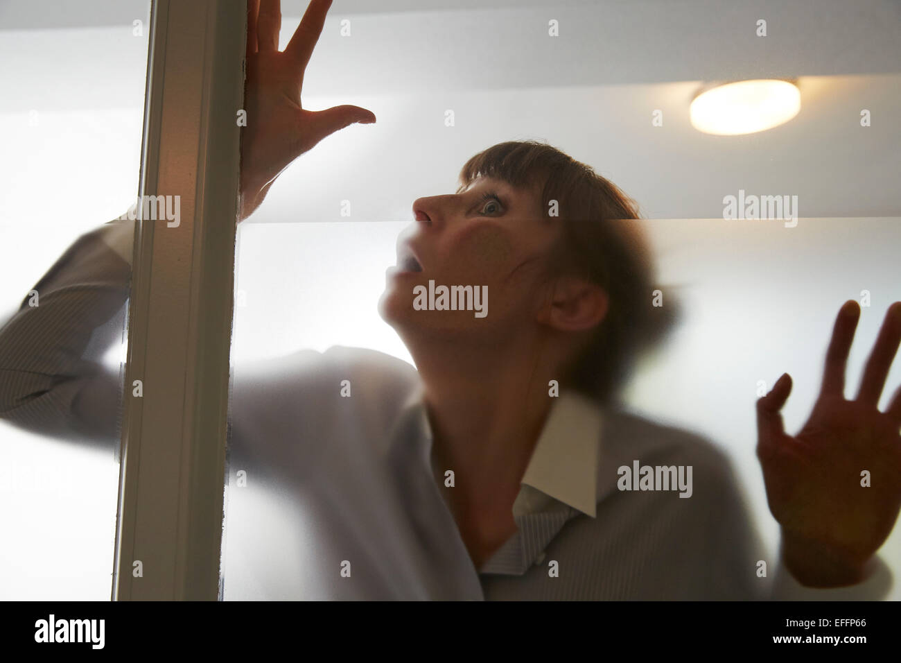 Frightened woman behind glass pane Stock Photo - Alamy