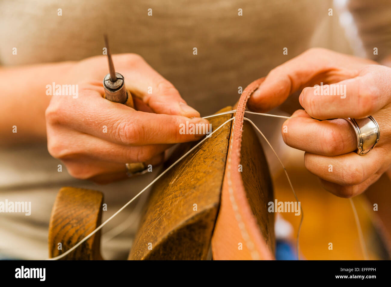 Woman sewing elastic fabric rubber band using lacing pony and awl Stock ...