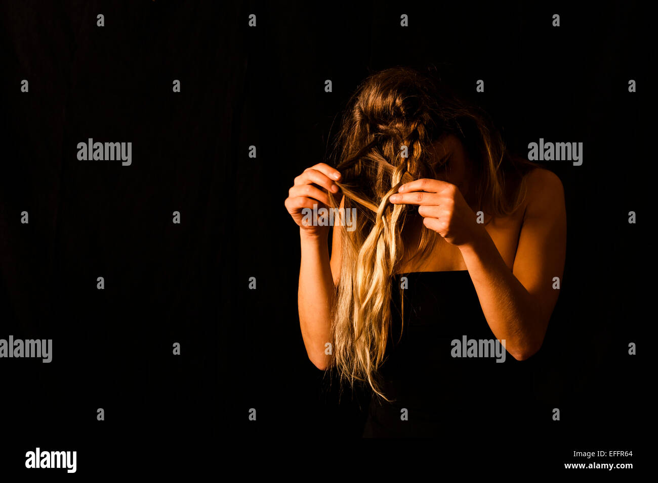 Woman disentangling her hair in front of black background Stock Photo ...