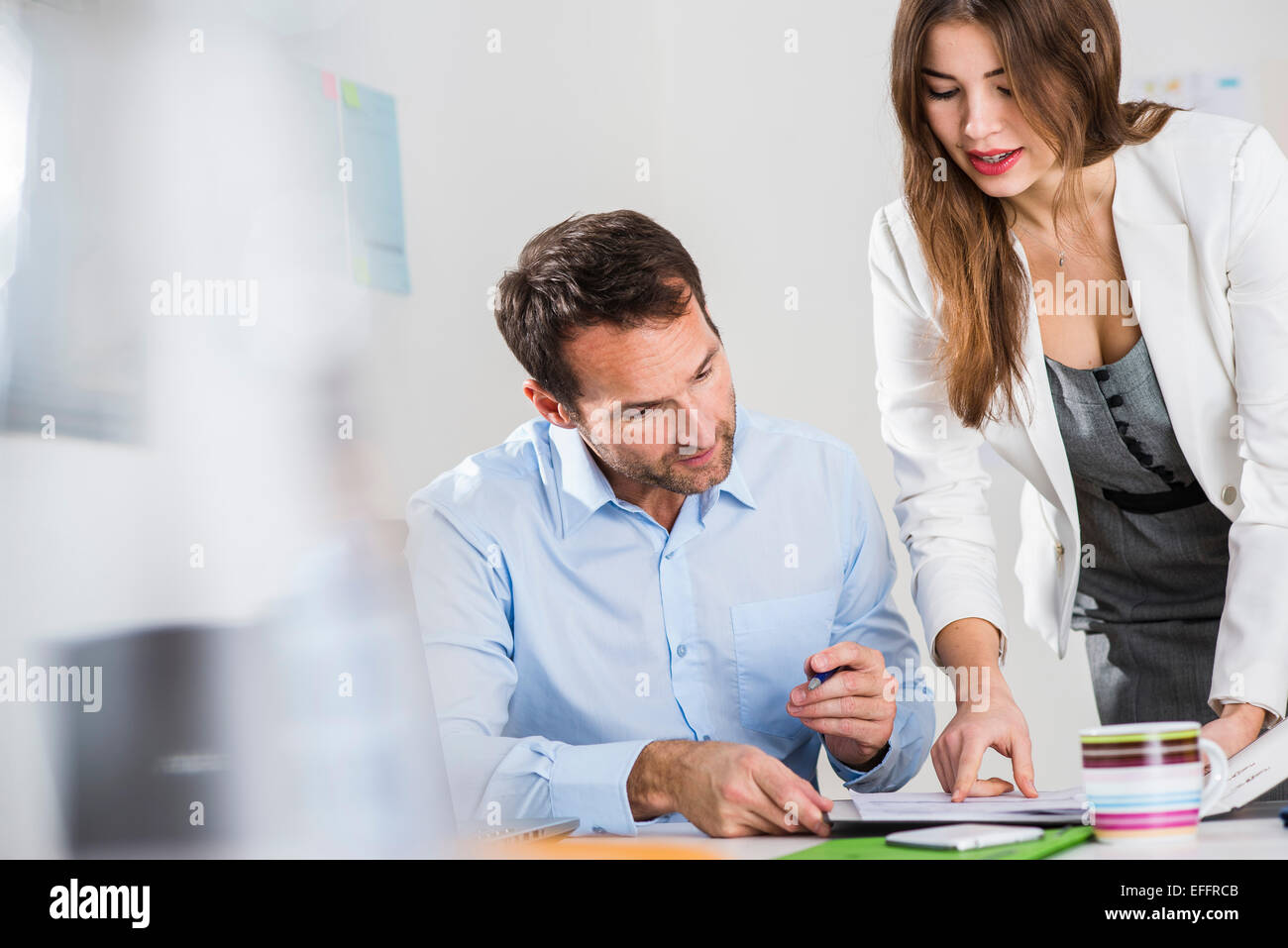 Businessman and secretary with file folder talking in office Stock ...