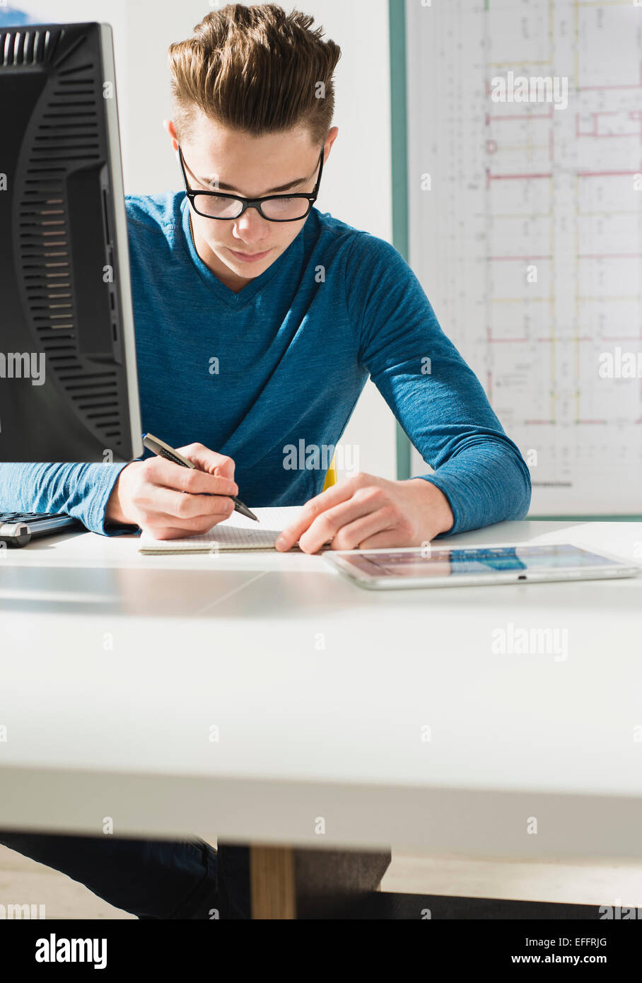 Young man at desk writing Stock Photo - Alamy