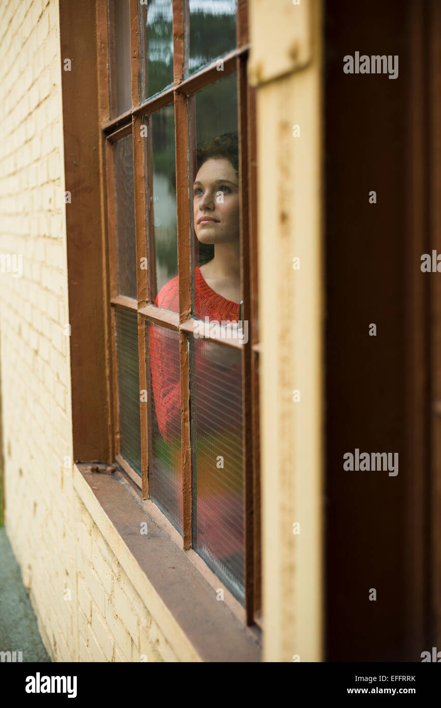 Young woman looking out of window Stock Photo - Alamy
