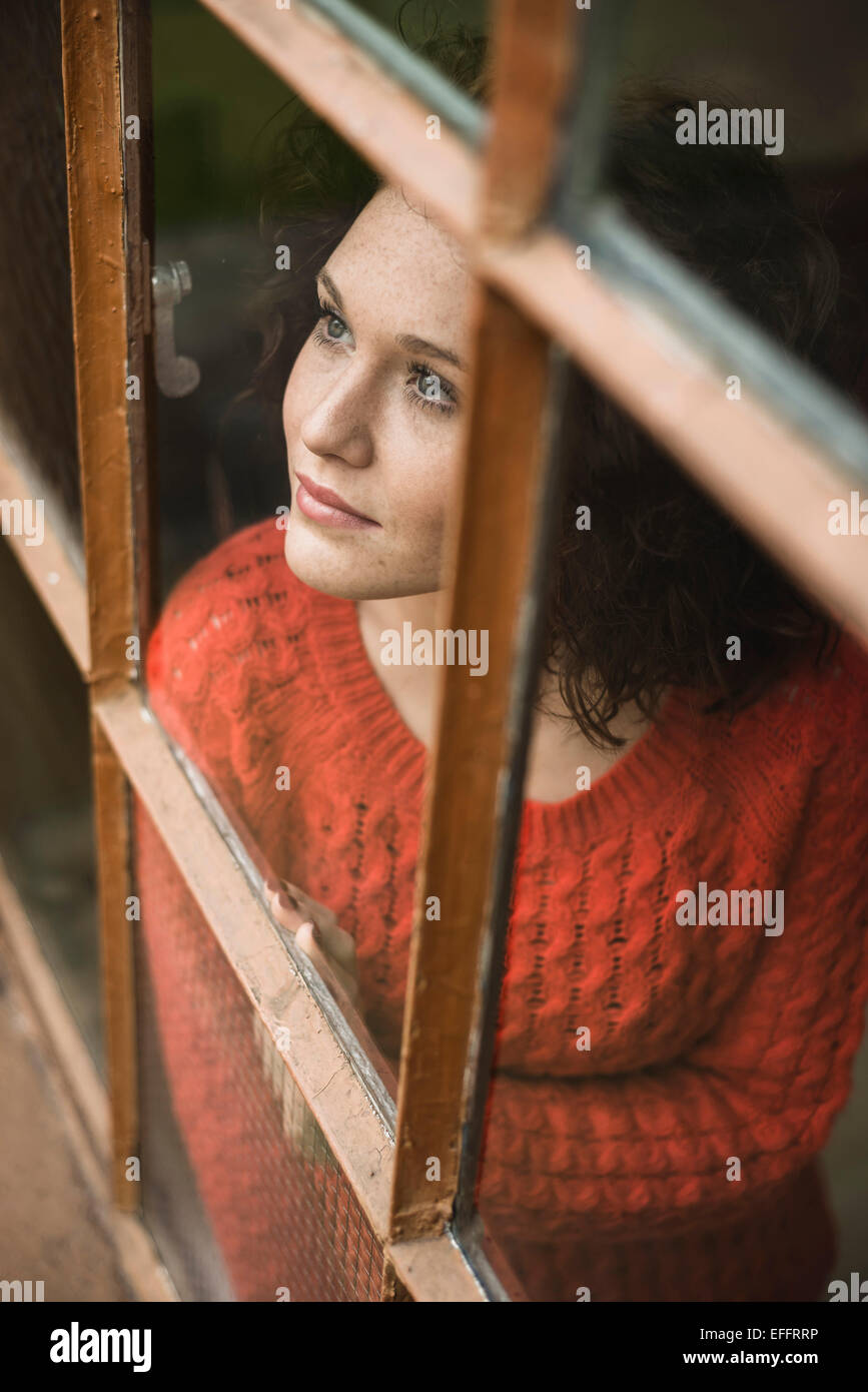 Young woman looking out of window Stock Photo - Alamy