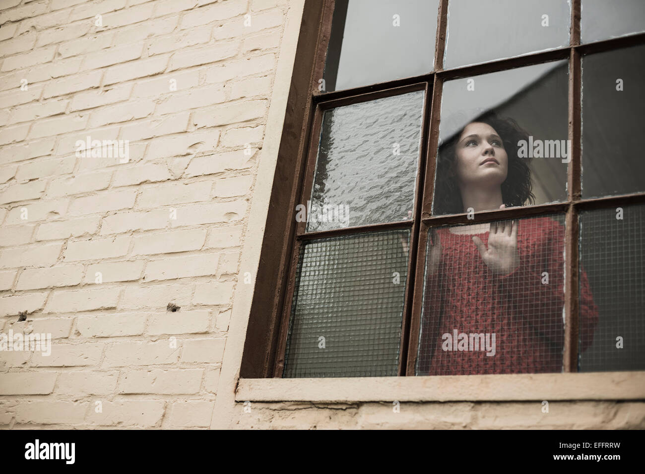 Young woman looking out of window Stock Photo - Alamy