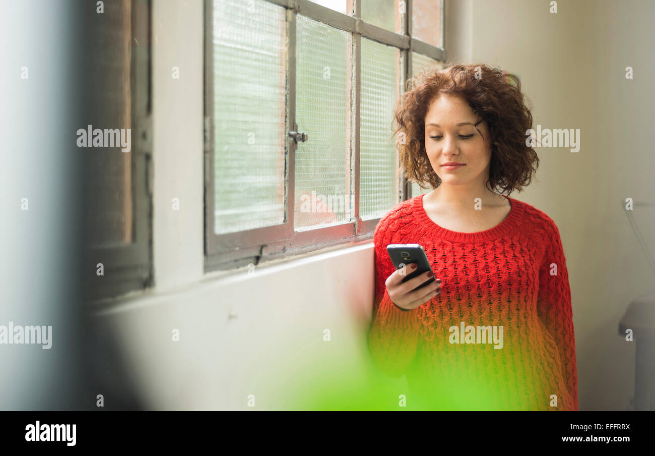 Young woman with cell phone at the window Stock Photo - Alamy